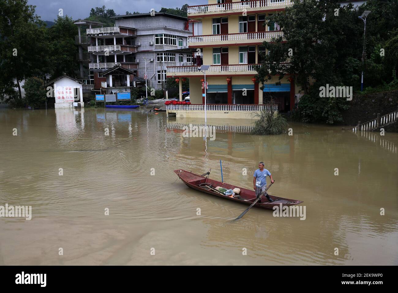 A person rows a boat to transport in flood caused by heavy rainfall in ...