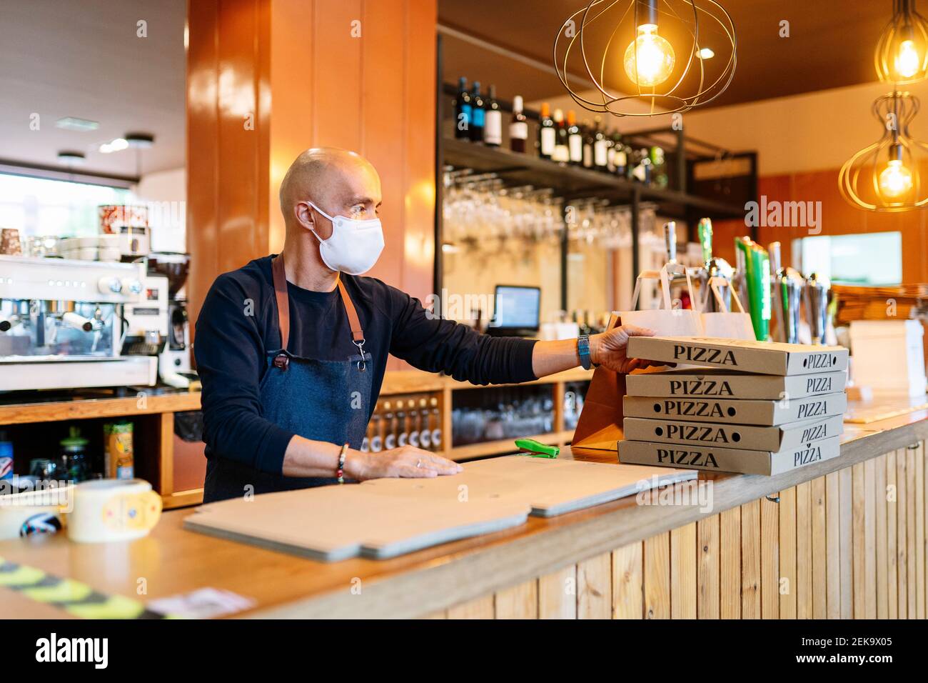 Mature male manager counting pizza boxes on counter while working ...