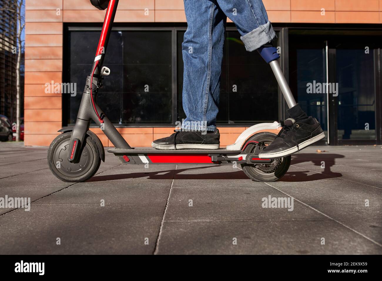 Young disabled man with prosthetic leg standing on electric push ...