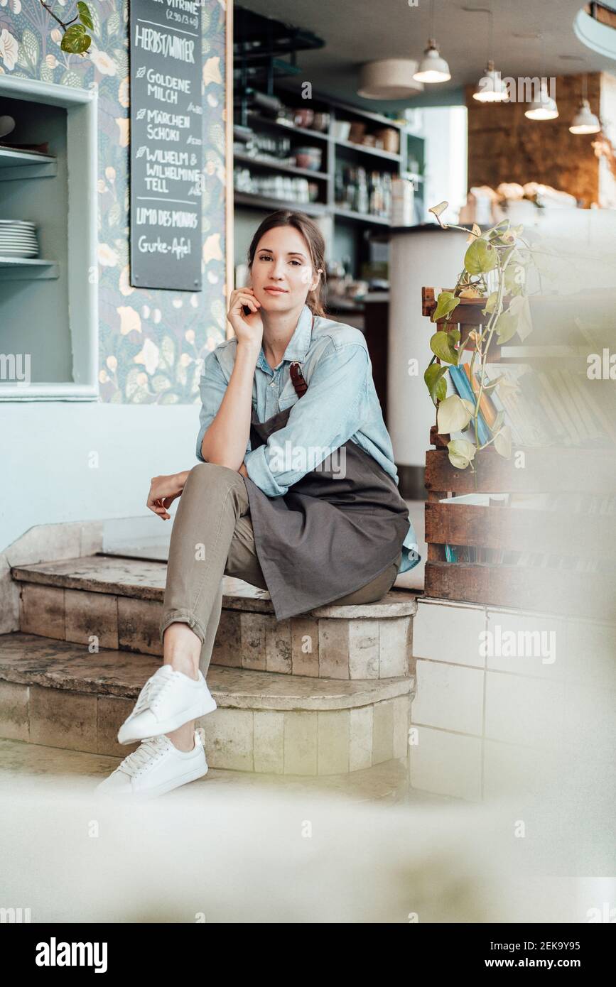 Female waitress sitting on steps at coffee shop Stock Photo - Alamy