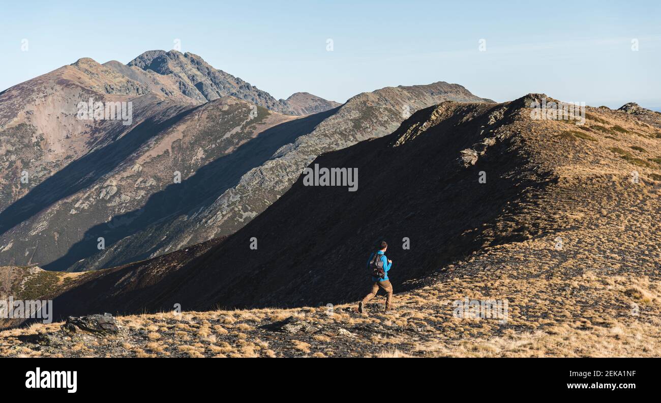 Male explorer running while trekking in mountain on sunny day Stock ...