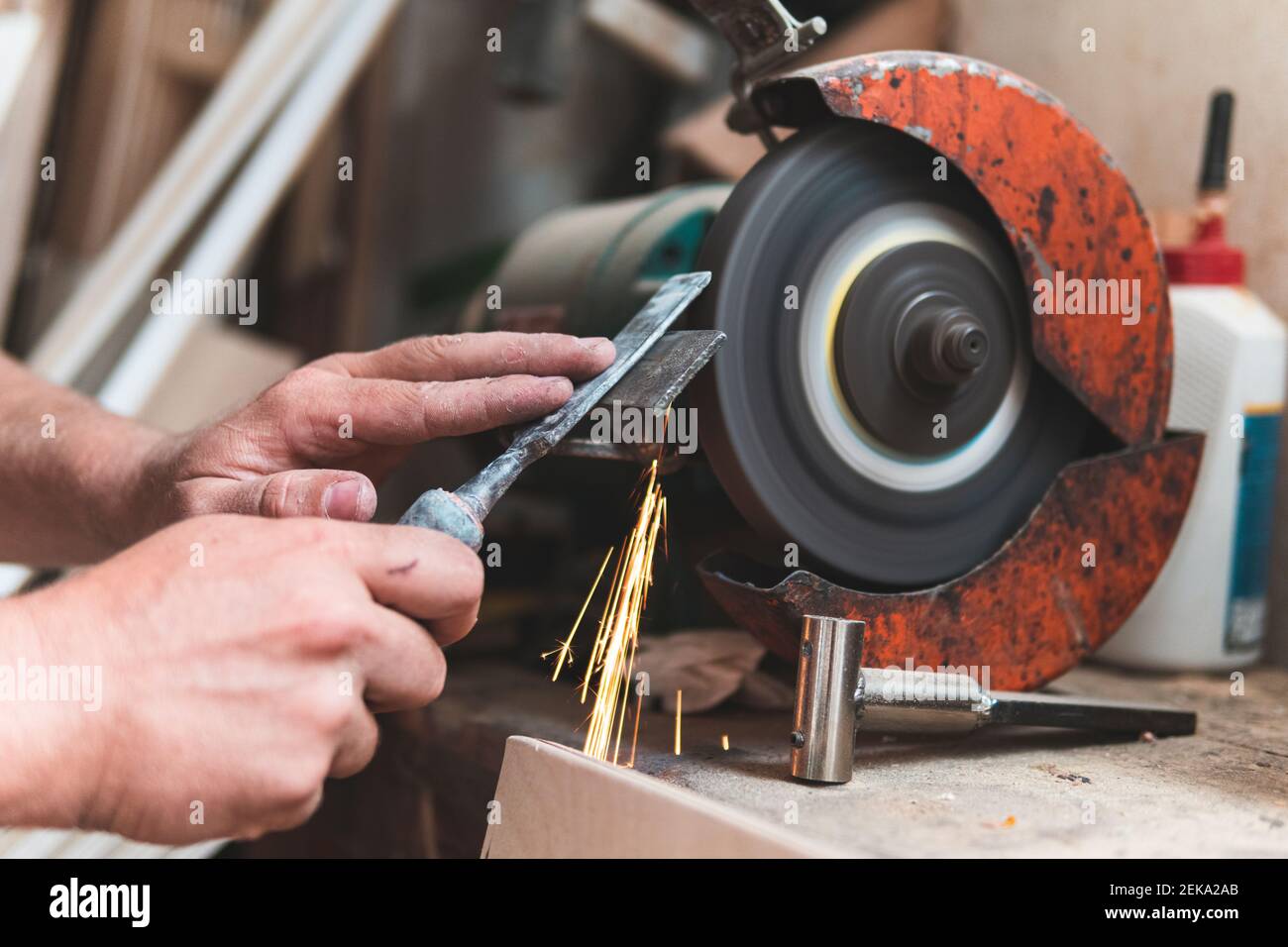 Male carpenter sharpening chisel using grinder in workshop Stock Photo ...
