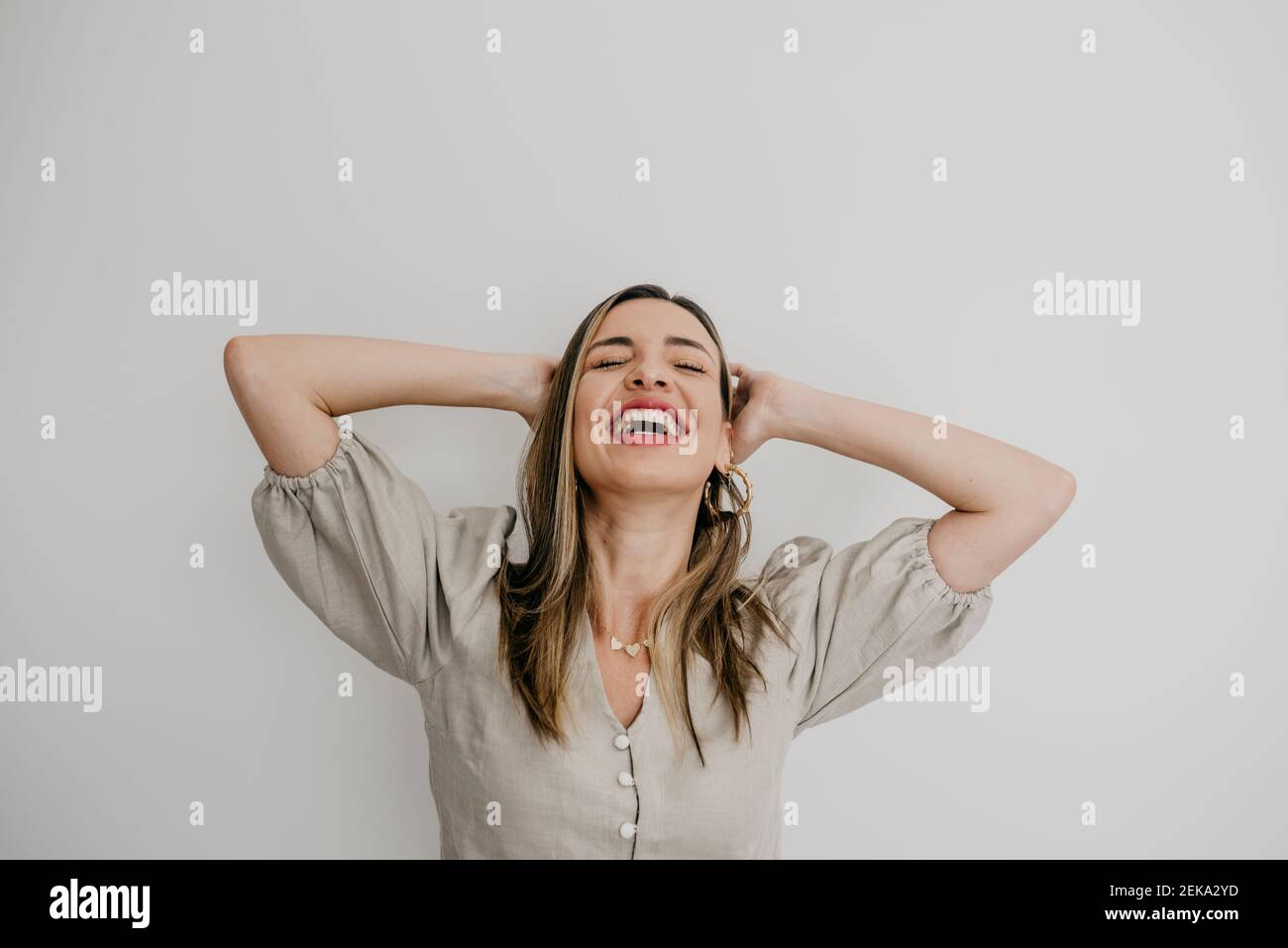 Laughing woman with hands behind head against white background Stock ...
