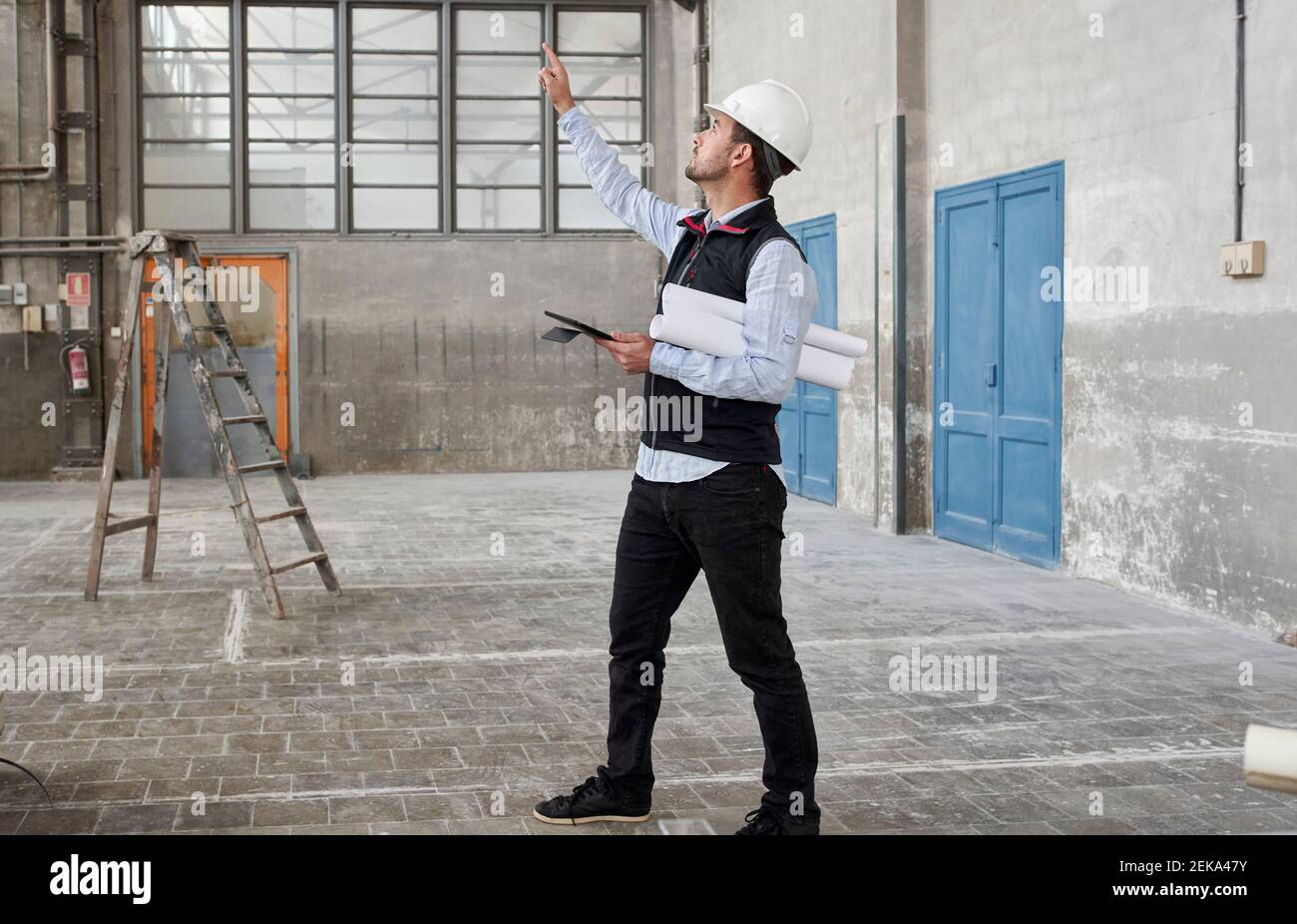 Male architect with digital tablet pointing while looking up in ...