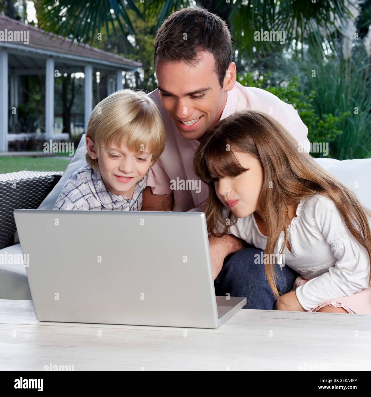 Man using a laptop with his children sitting beside him Stock Photo - Alamy