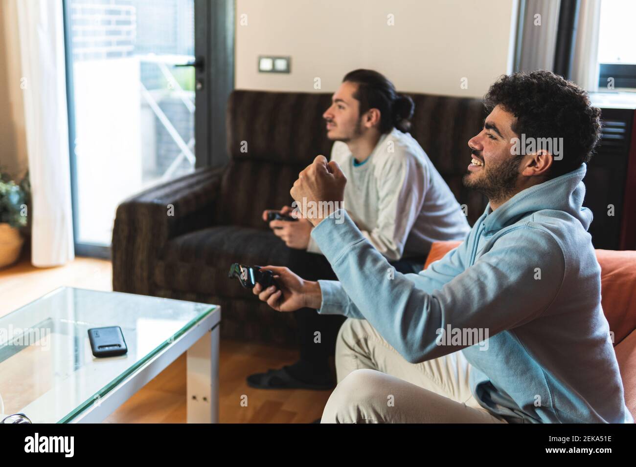 Cheerful friends playing video game in living room at home Stock Photo ...