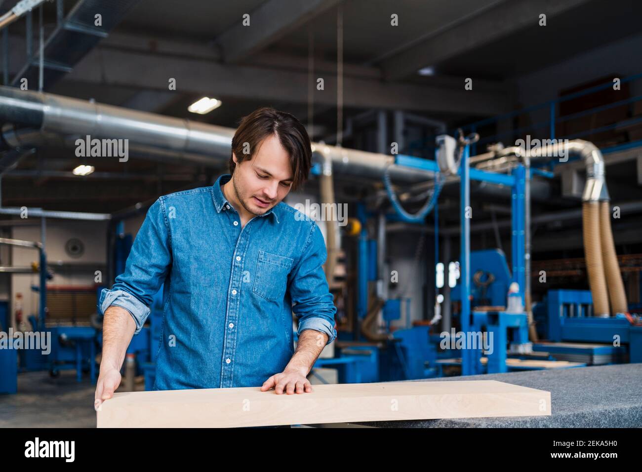 Manual worker checking plank while standing at industry Stock Photo - Alamy