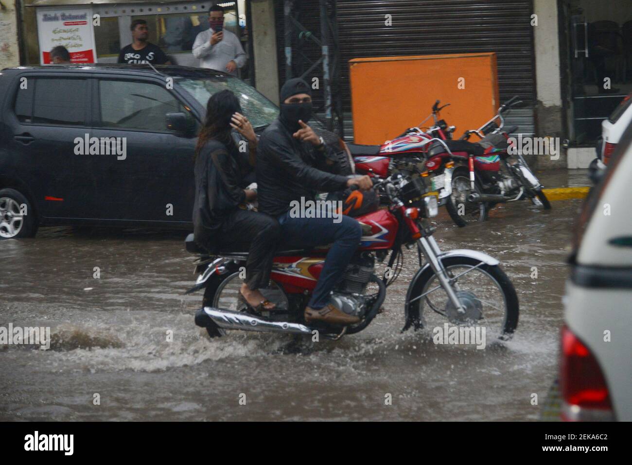 Pakistani commuters wade through a flooded street after heavy monsoon rain spell in provincial ...