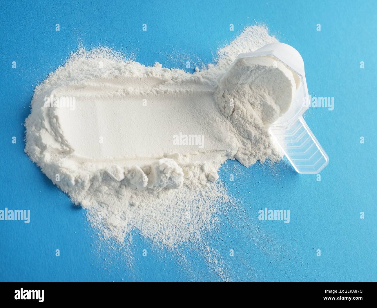 Measuring spoon with protein powder on a blue background, nutritional ...