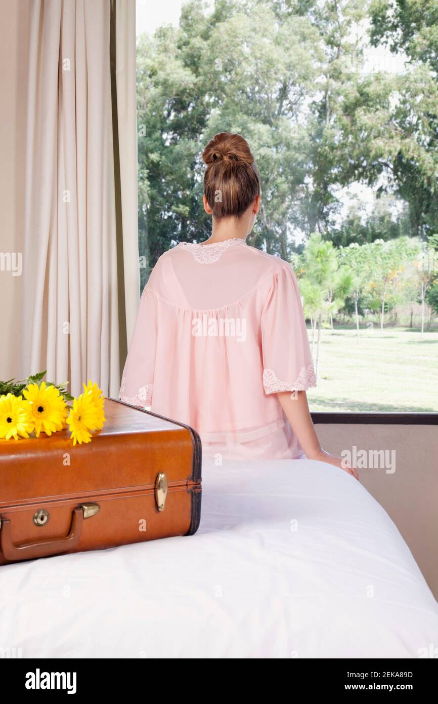 Rear view of a woman looking through a window Stock Photo - Alamy