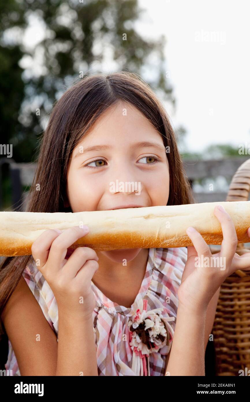 Girl biting a loaf of bread Stock Photo - Alamy