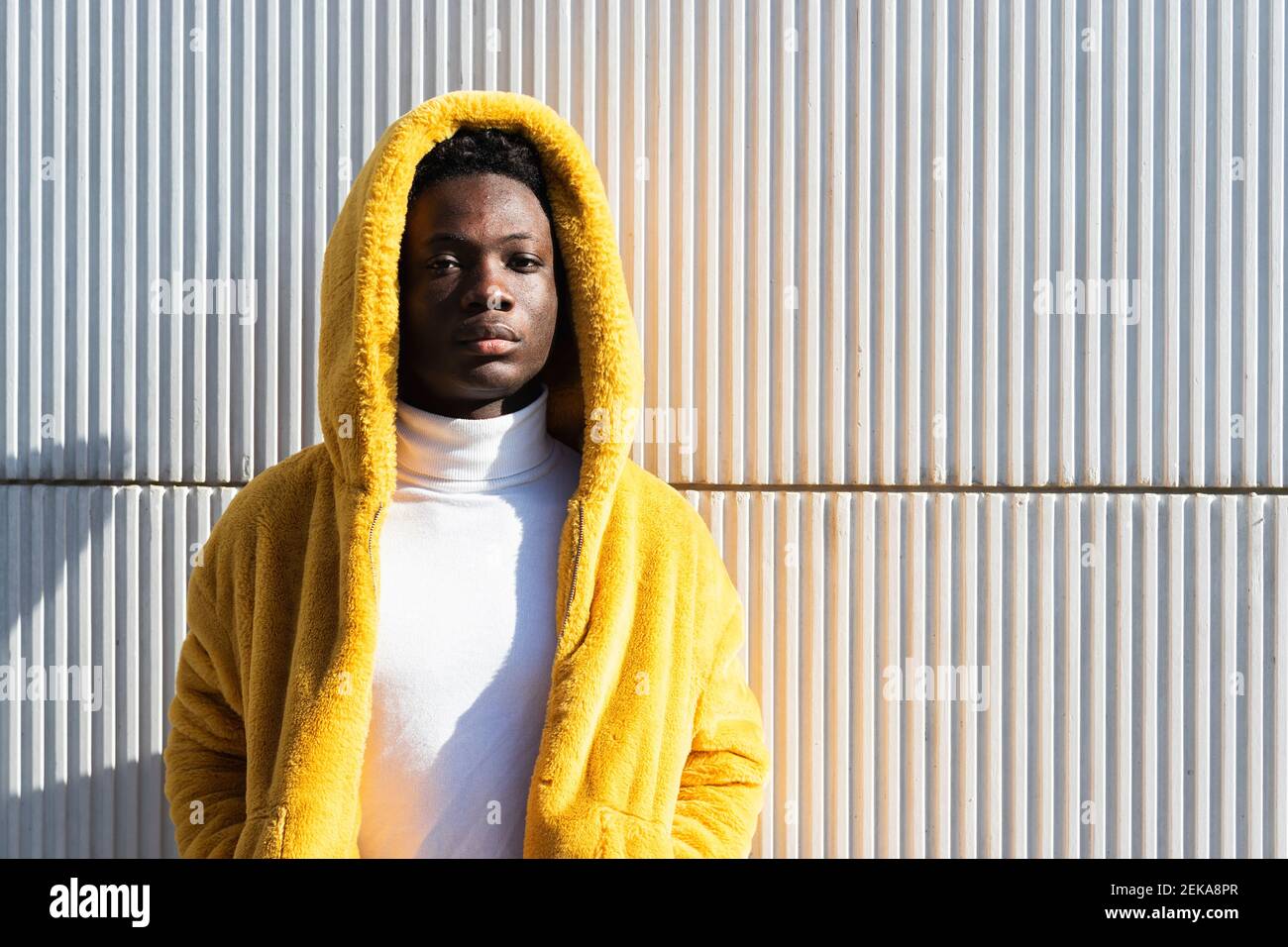 Young man in yellow jacket against white wall Stock Photo - Alamy