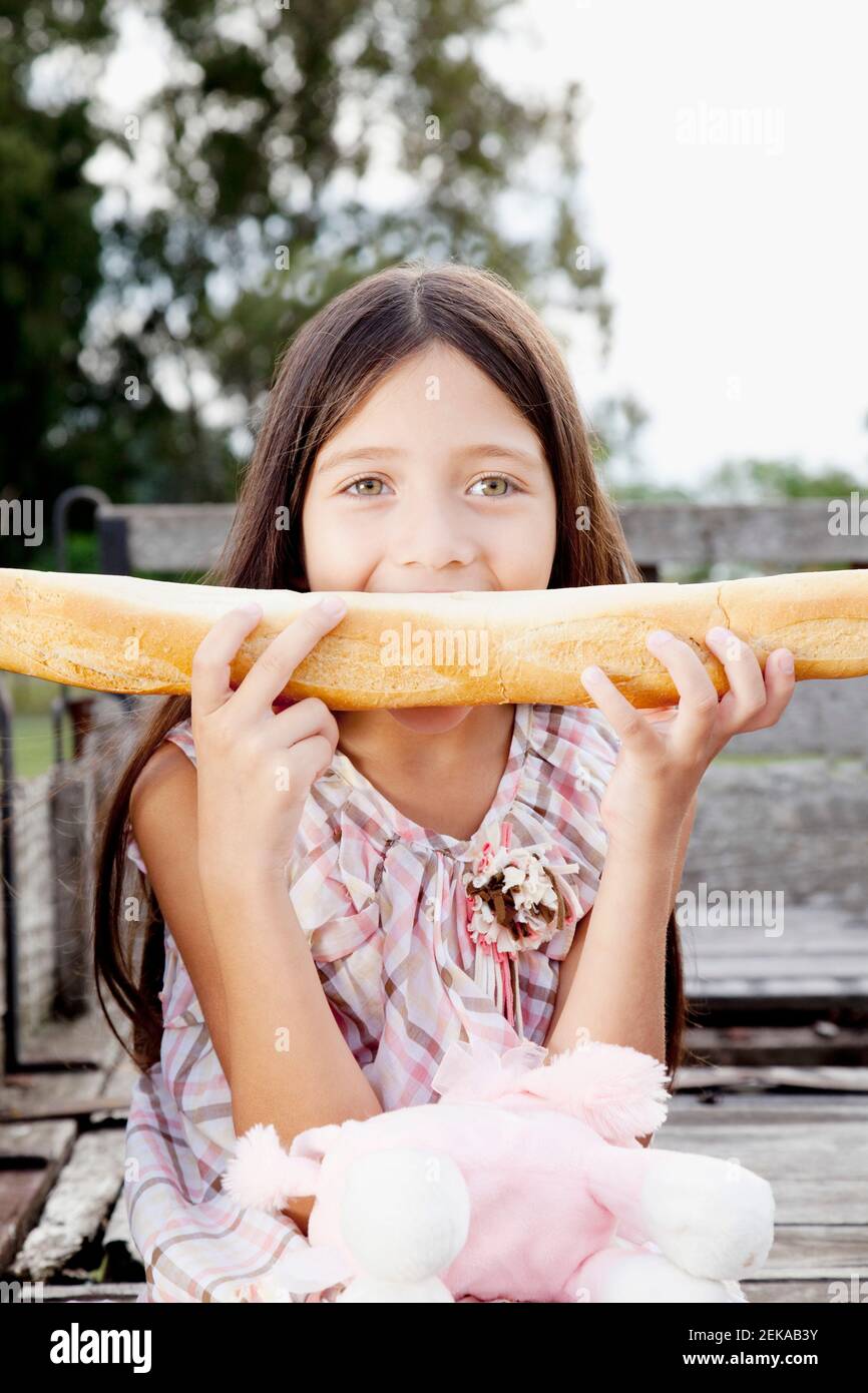 Girl biting a loaf of bread Stock Photo - Alamy