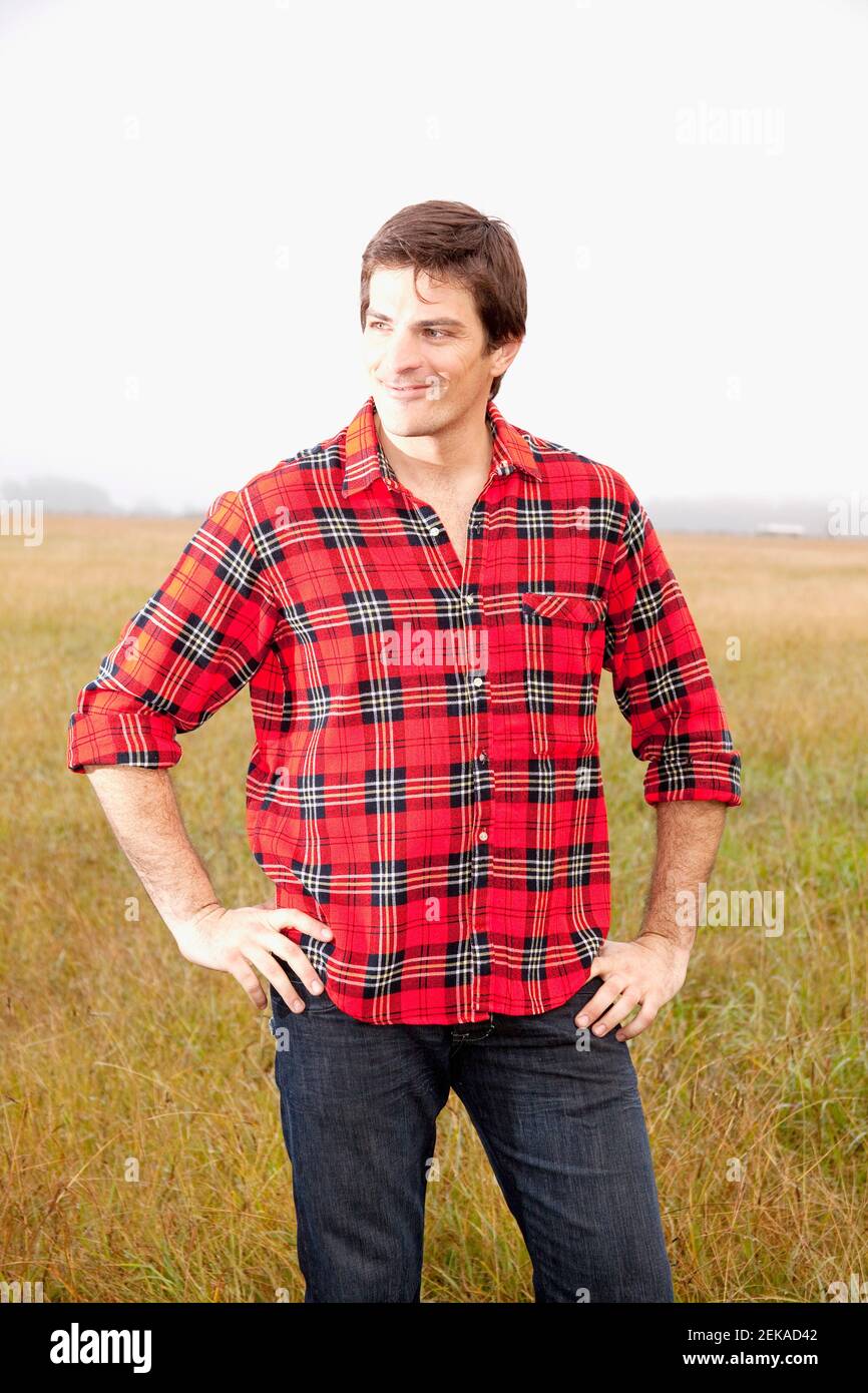 Man standing in a field with arms akimbo Stock Photo - Alamy