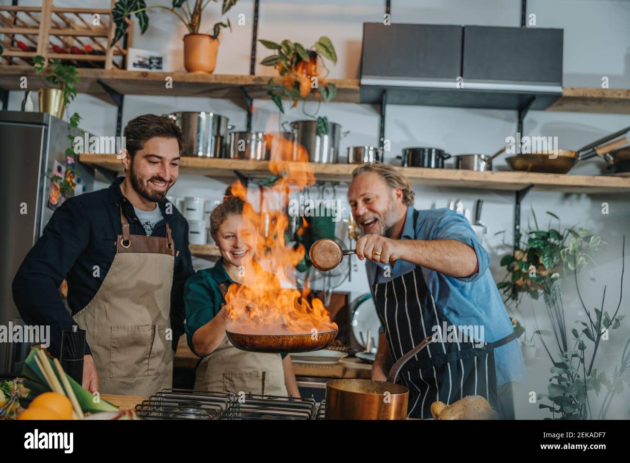 Young chef learning stirring food in frying pan while standing by ...