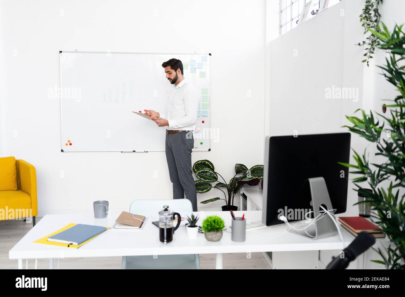 Male professional examining document on clipboard while standing by ...