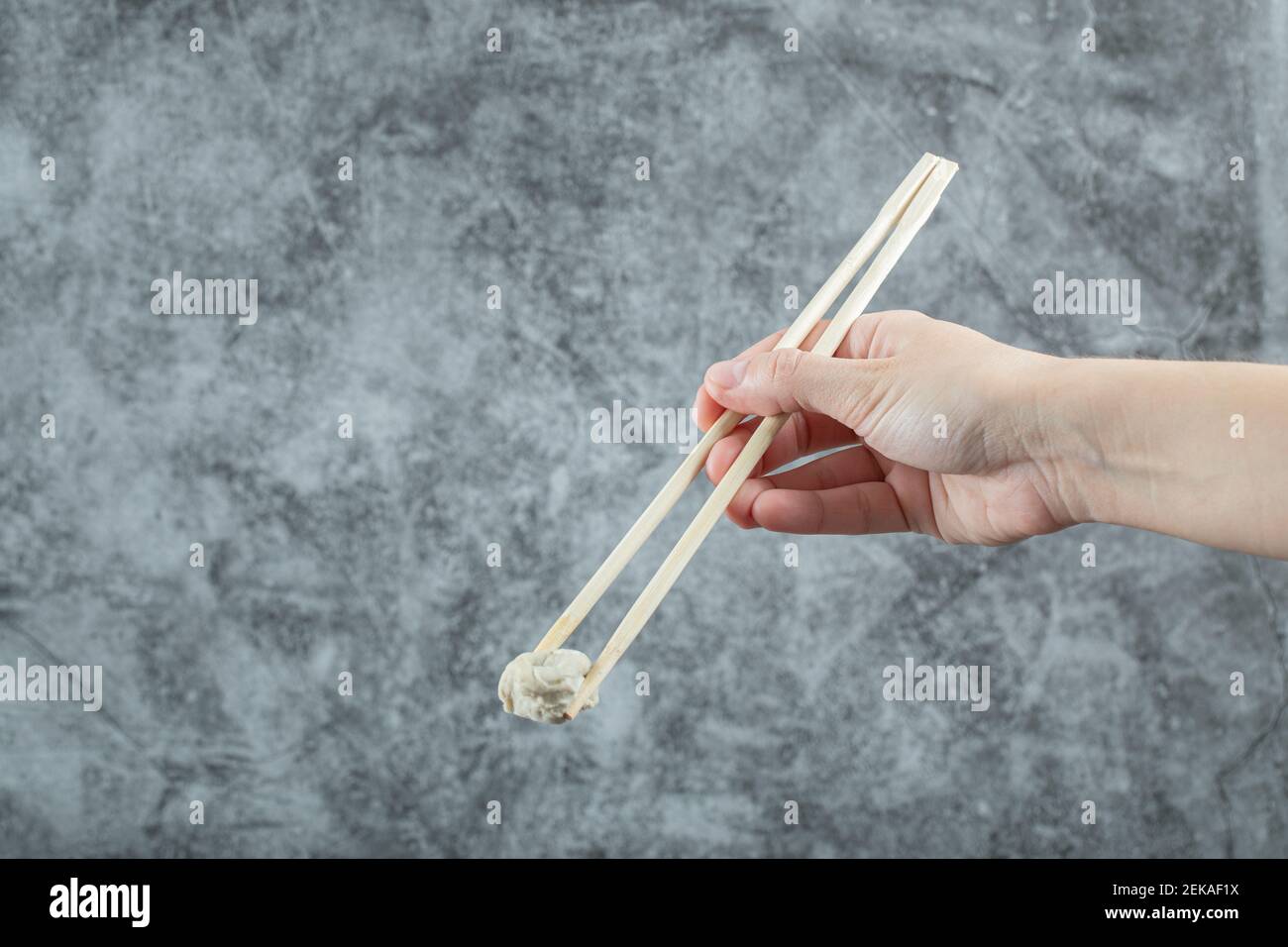 Hand holding a chopstick with a dumpling Stock Photo - Alamy