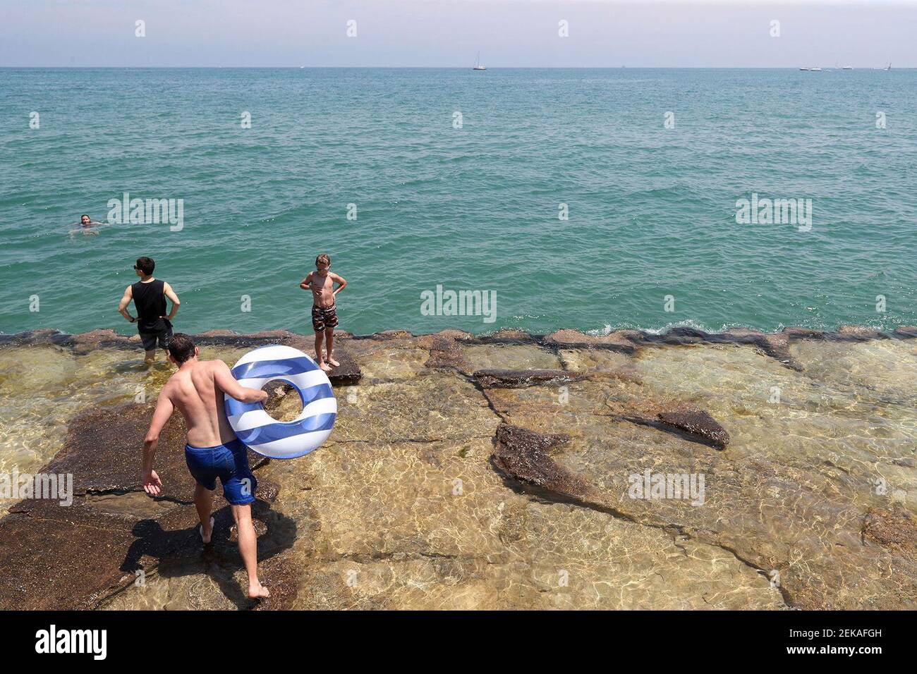 Kevin Schafer carries an inflatable tube to the water south of Foster ...