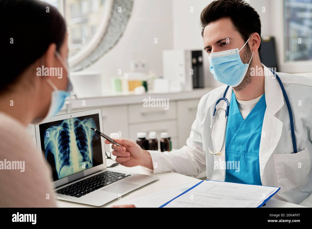 Male doctor explaining medical X-ray on laptop to female patient in ...