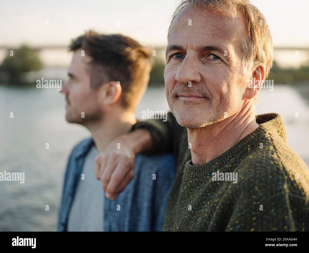 Smiling father by son at riverbank Stock Photo - Alamy