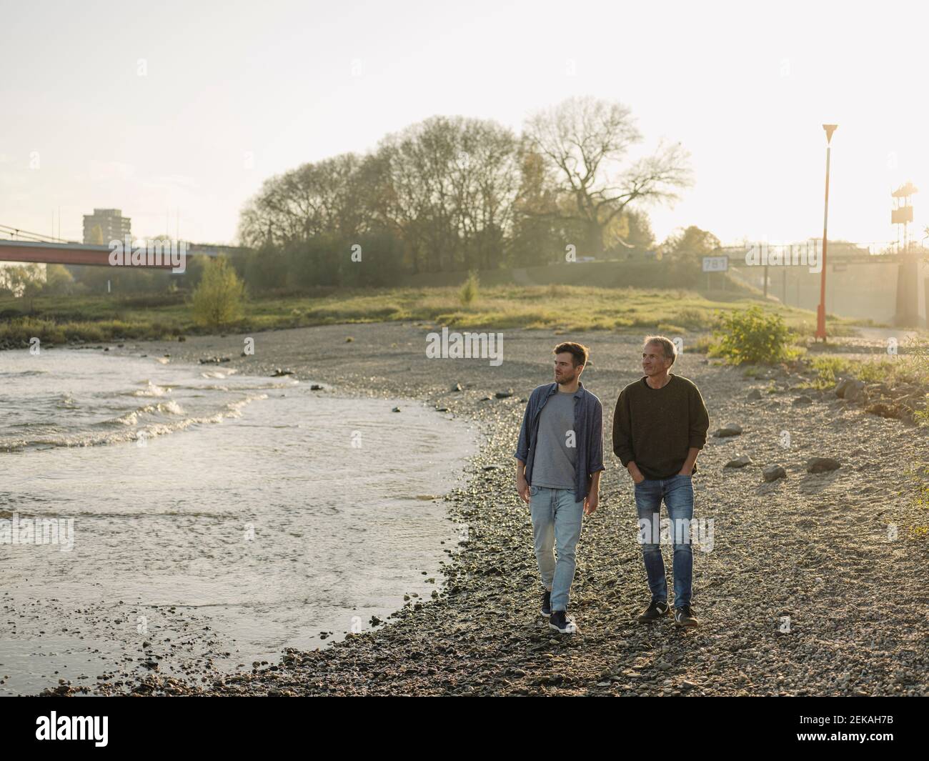 Son and father looking away while walking at riverbank Stock Photo - Alamy