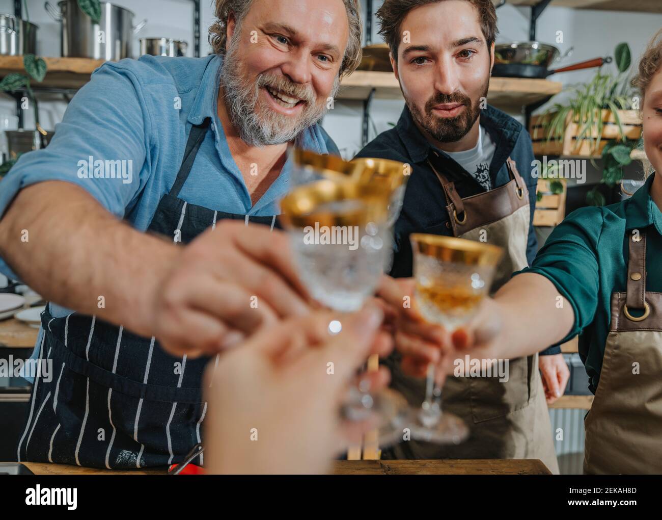 Chefs toasting drinks with woman drinking glass while standing in ...