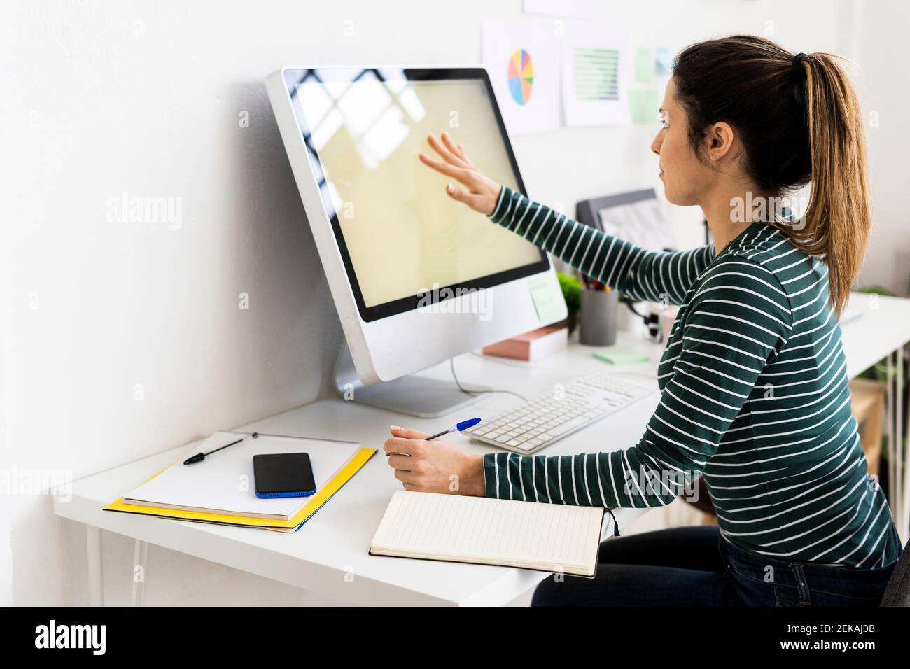 Creative businesswoman touching computer screen while working in office ...