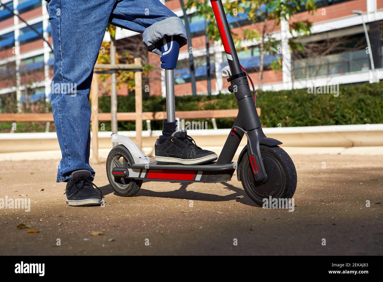 Disabled man with prosthetic leg standing on electric push scooter in ...