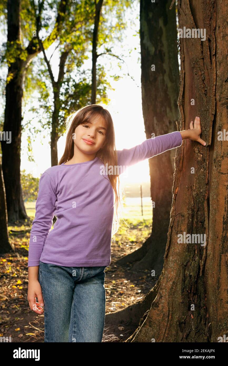 Girl leaning against a tree in a garden Stock Photo - Alamy