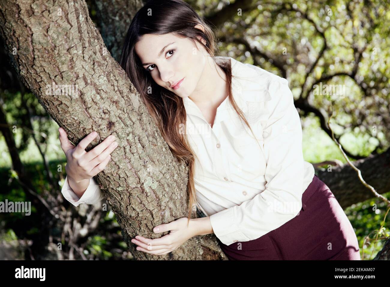 Portrait of a teenage girl hugging a tree in a park Stock Photo - Alamy