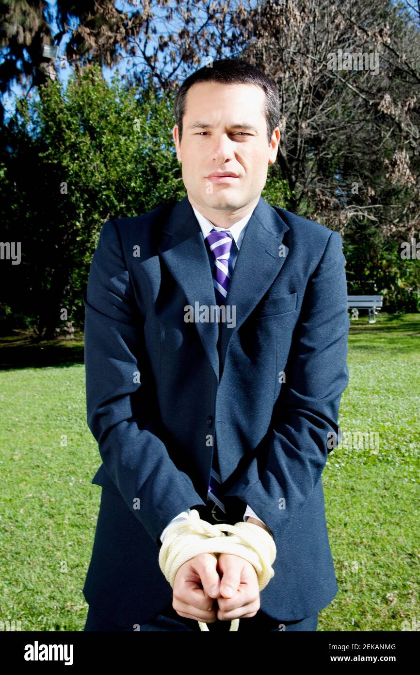 Businessman tied up with a rope Stock Photo - Alamy
