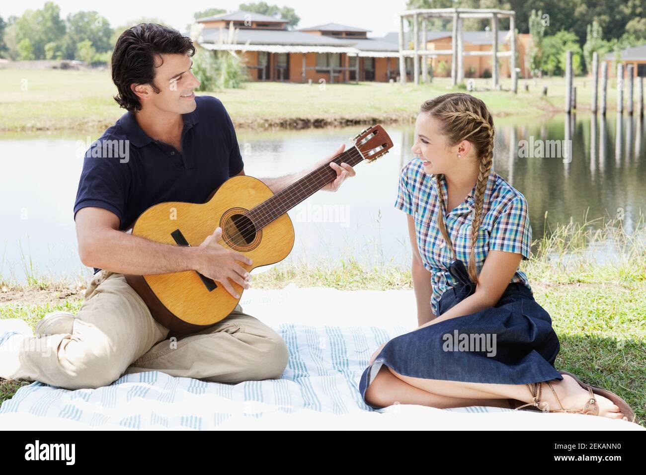 Man playing guitar with a woman sitting in front of him Stock Photo - Alamy