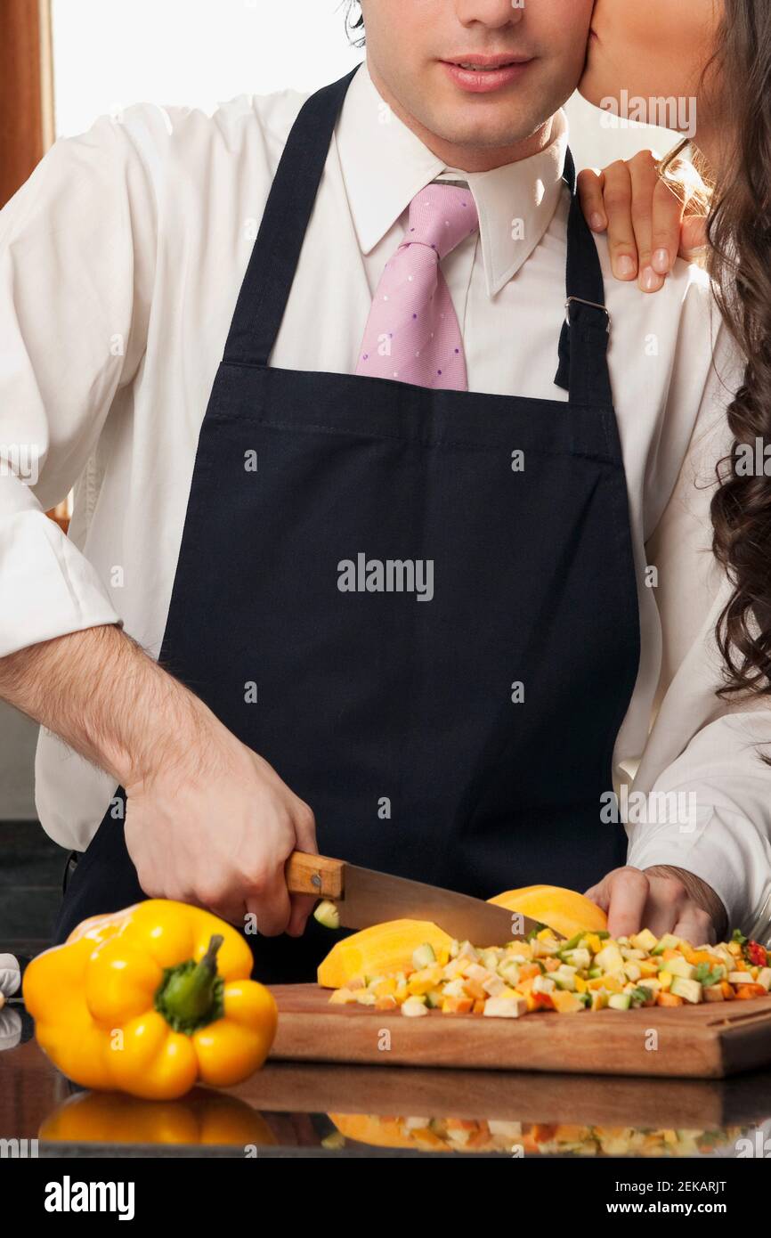 Man preparing food with his wife kissing him Stock Photo - Alamy