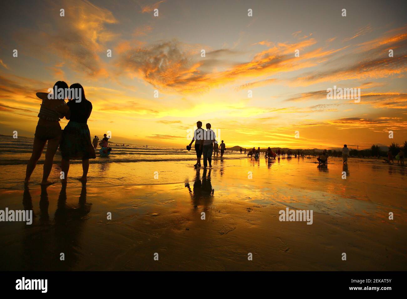 People play by the beach at Sanya Bay against the sunset in Sanya city ...