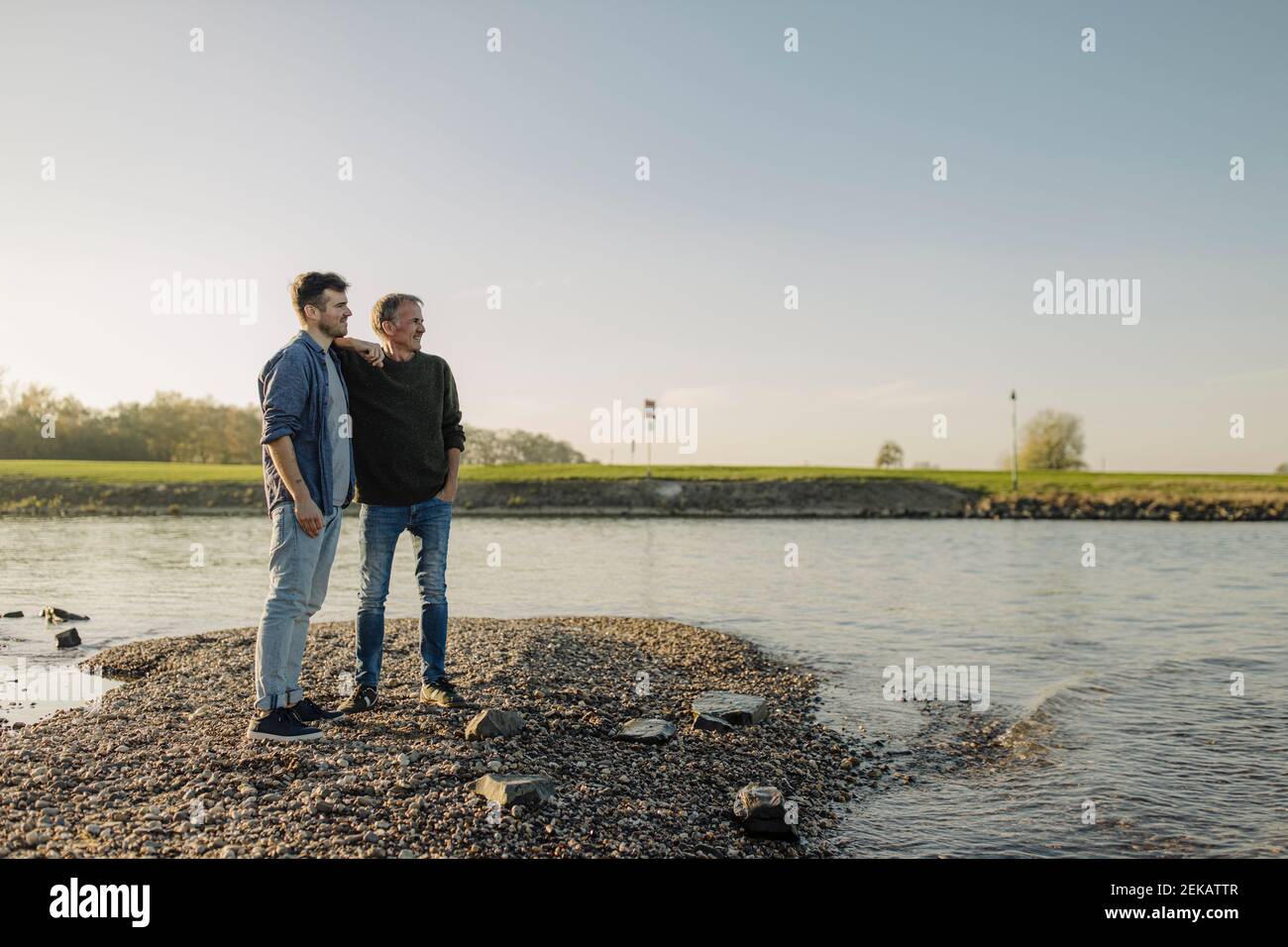 Son and father looking away while standing against clear sky at ...