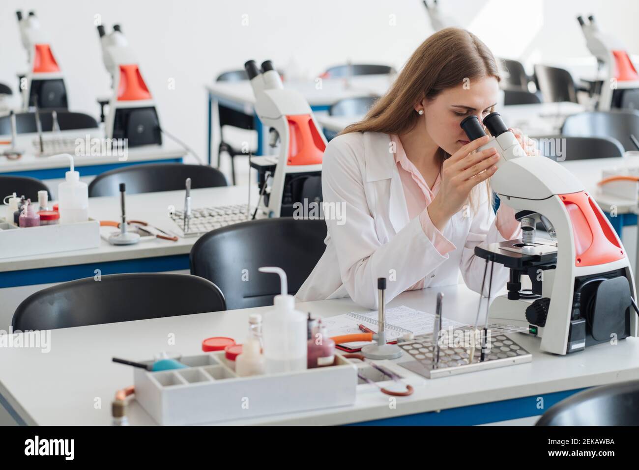 Young researcher in white coat working with microscope in lab Stock ...