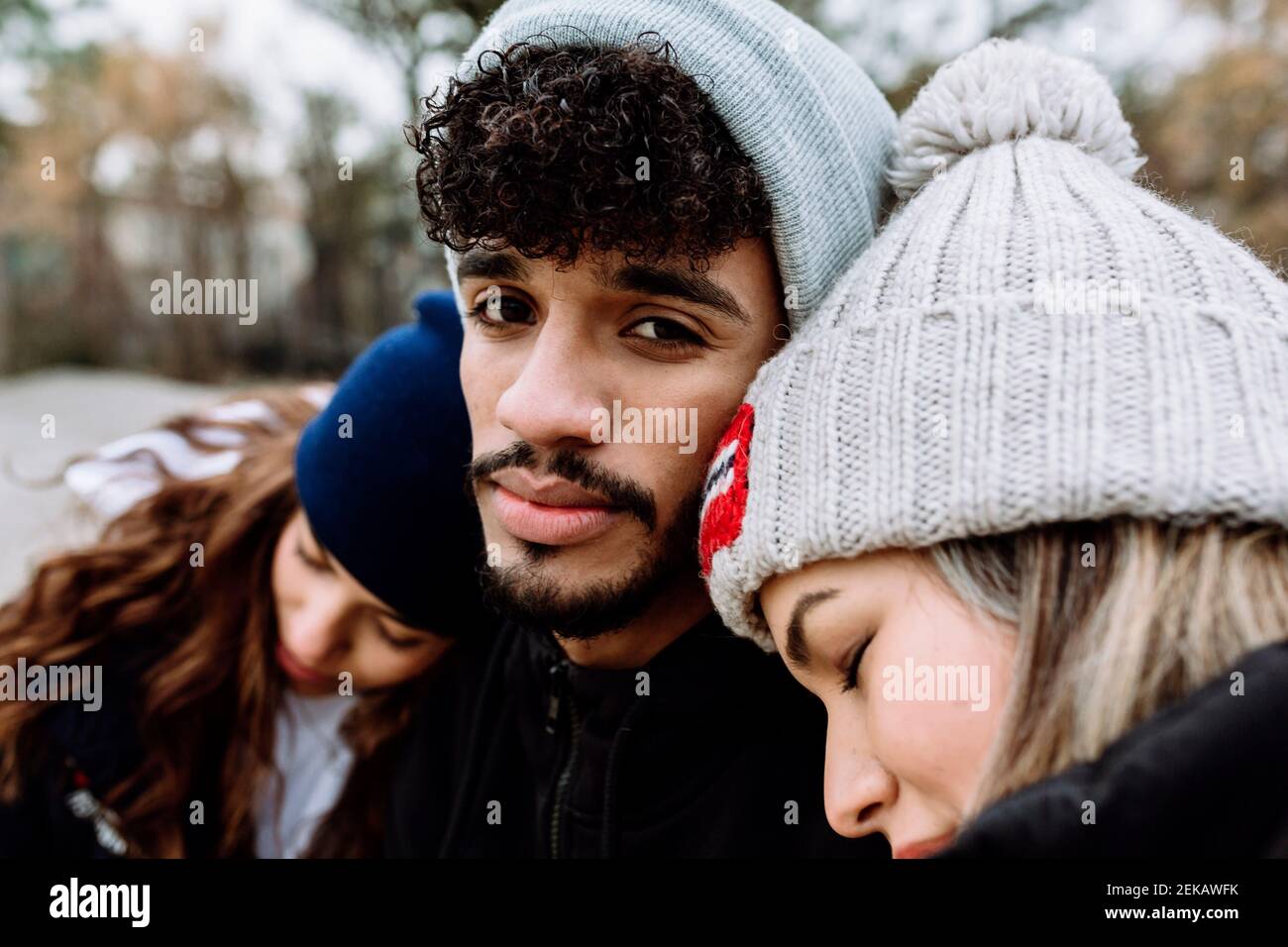 Female friends leaning on male friend shoulder at park Stock Photo - Alamy