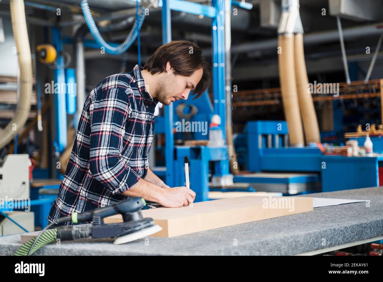 Industrial worker measuring plank while working at industry Stock Photo ...