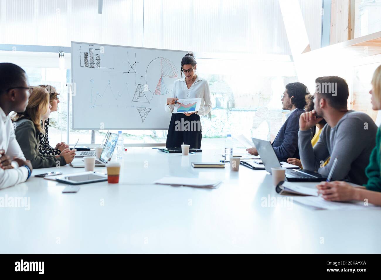 Businesswoman explaining strategy to colleagues over digital tablet on ...