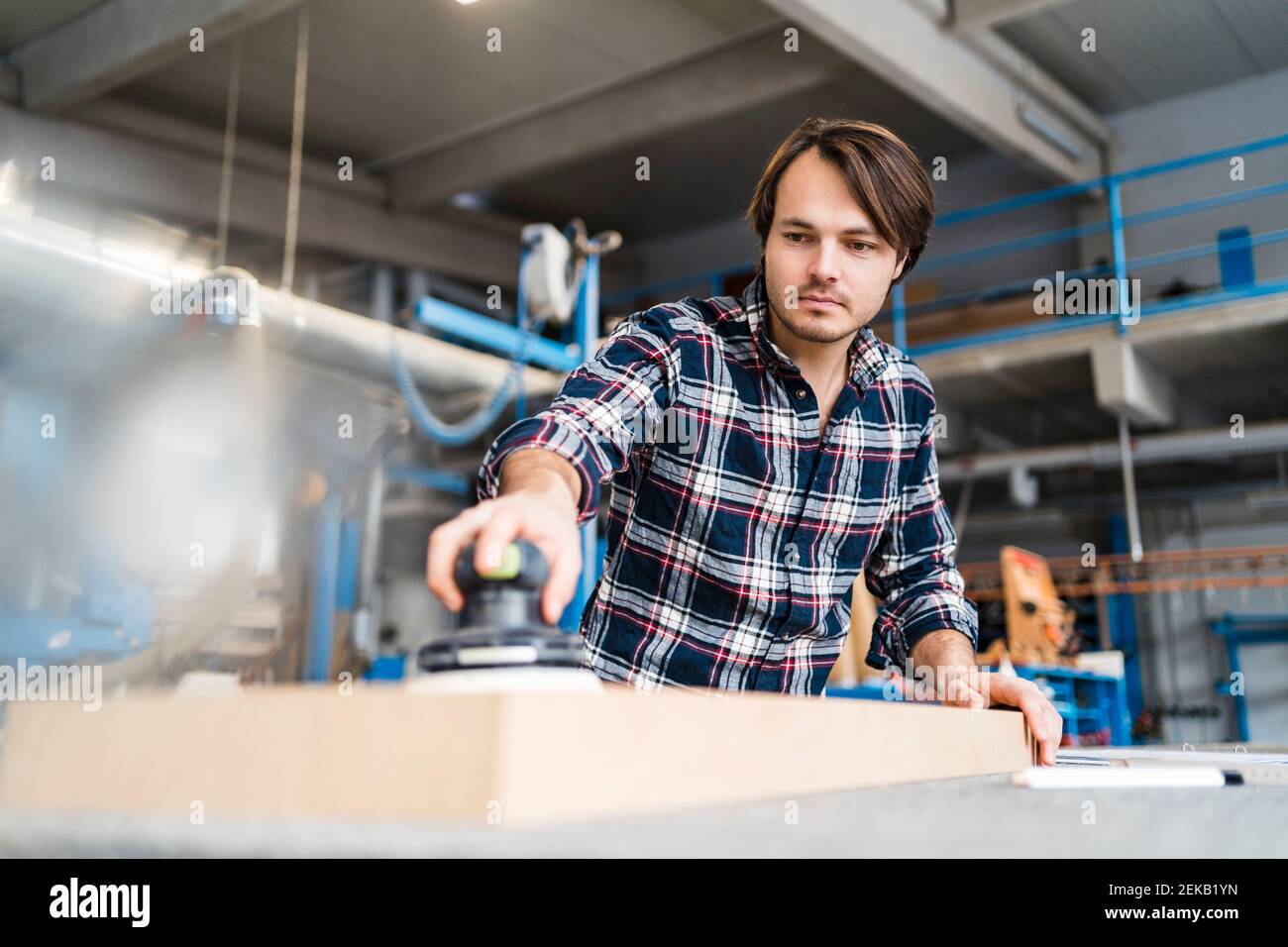 Manual worker using sander on plank while working at industry Stock ...