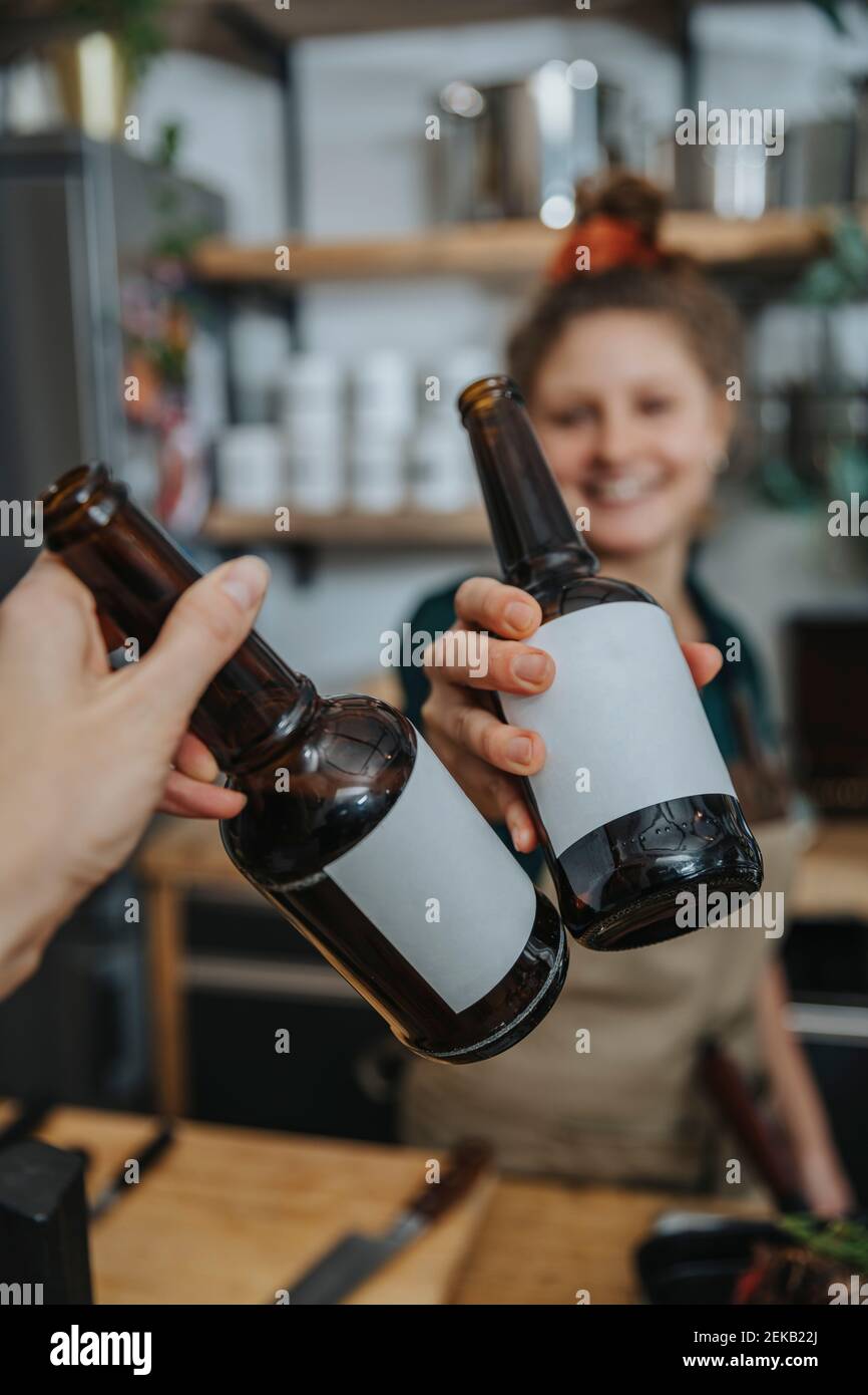 Chef toasting beer bottle with woman while standing in kitchen Stock ...