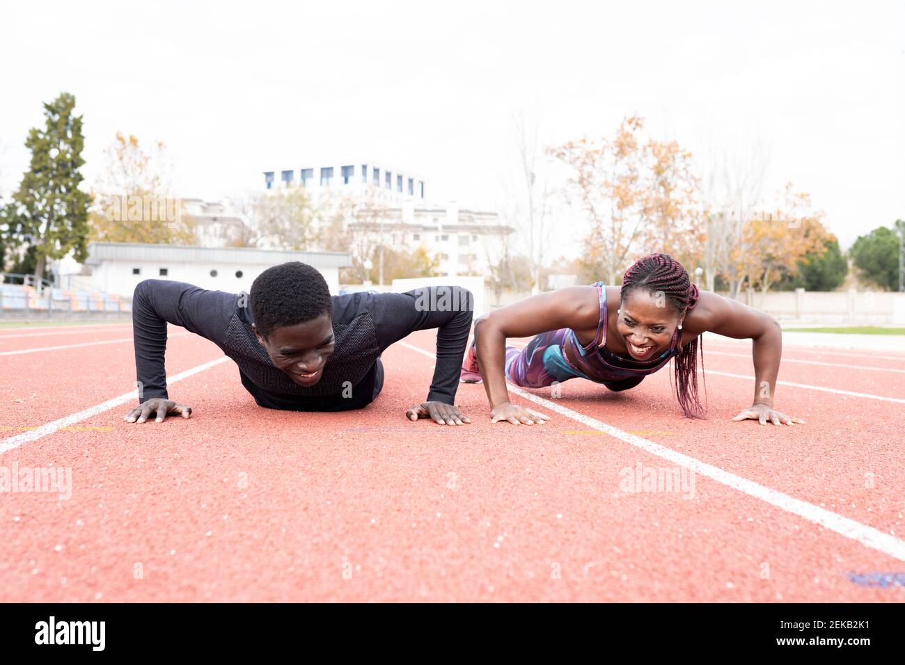 Happy male and female sportsperson doing push ups on running track ...