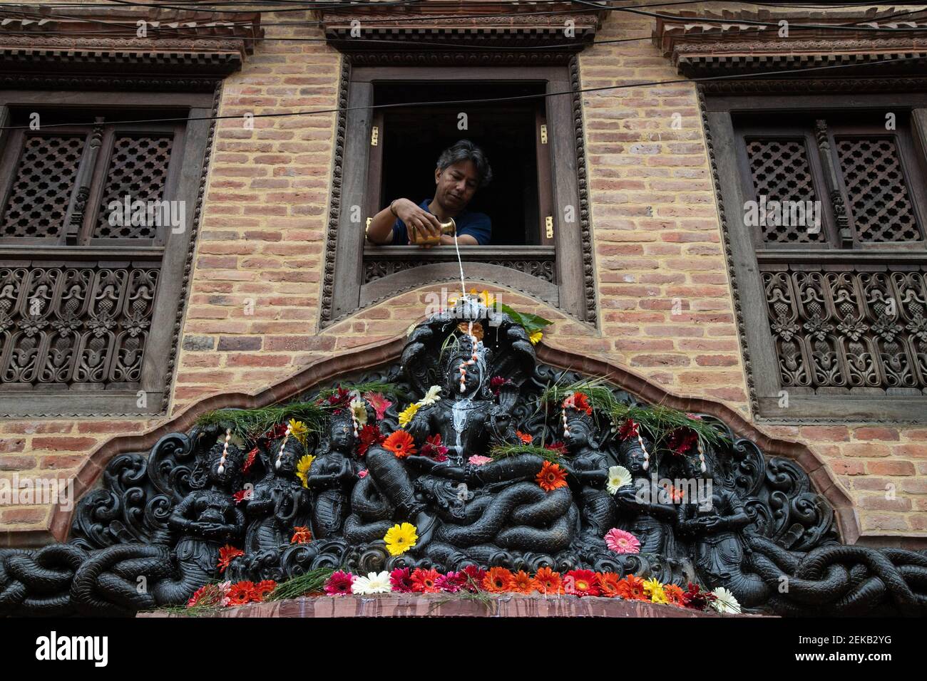 A Hindu devotee pays his respect by pouring cow milk over a statue of ...