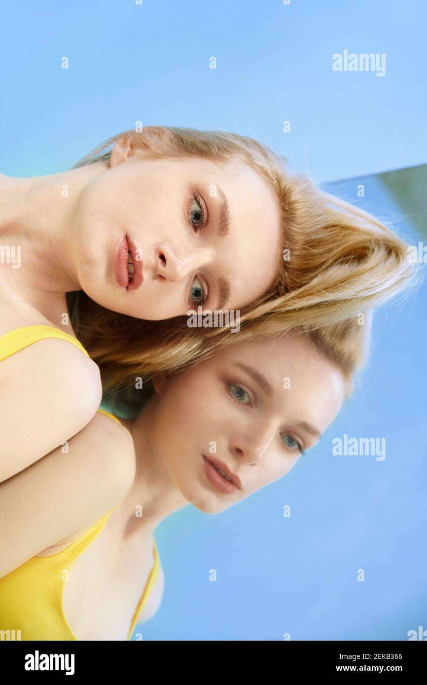 Beautiful woman lying down on mirror against blue background Stock ...