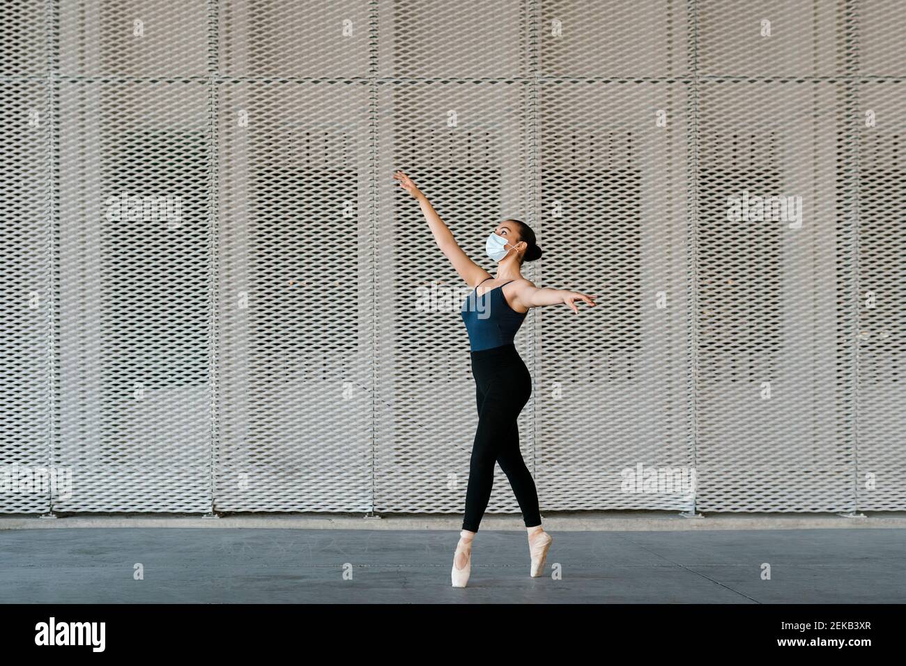 Female ballet dancer standing on tiptoe while practicing against metal ...