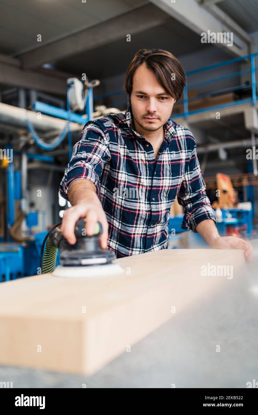 Manual worker sanding wood with sander while standing at industry Stock ...