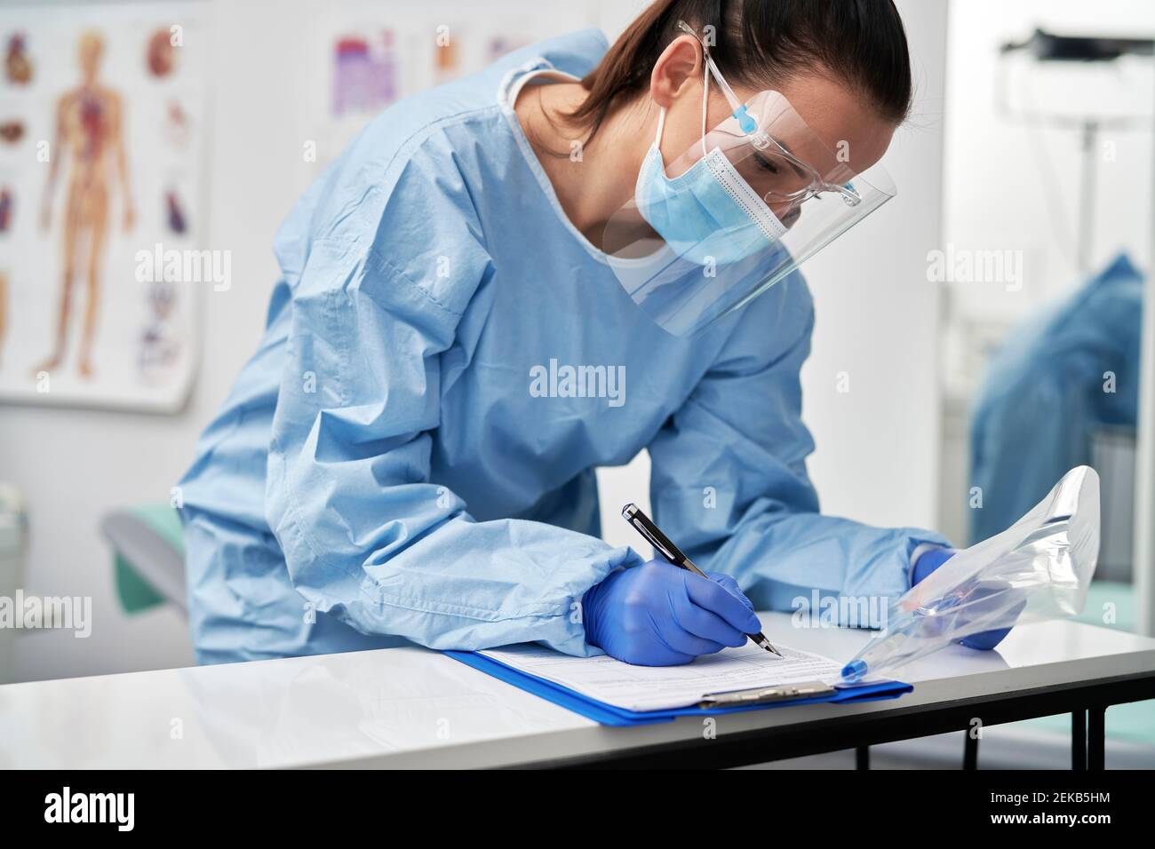 Mature female doctor completing documents related to medical sample in ...