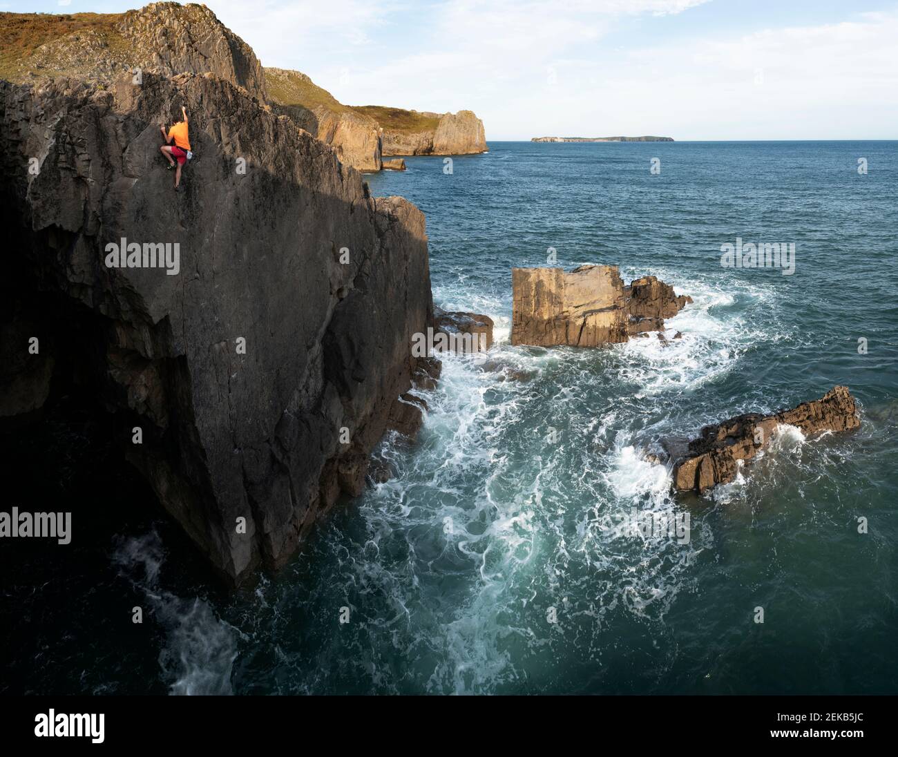Male rock climber reaching on top of cliff Stock Photo - Alamy