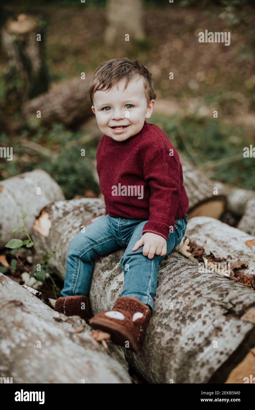 Boy sitting on log in forest hi-res stock photography and images - Alamy