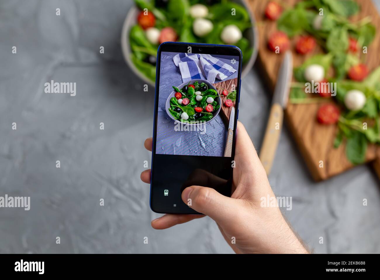 Man shooting fresh vegetable salad with mozzarella and spinach on cell ...